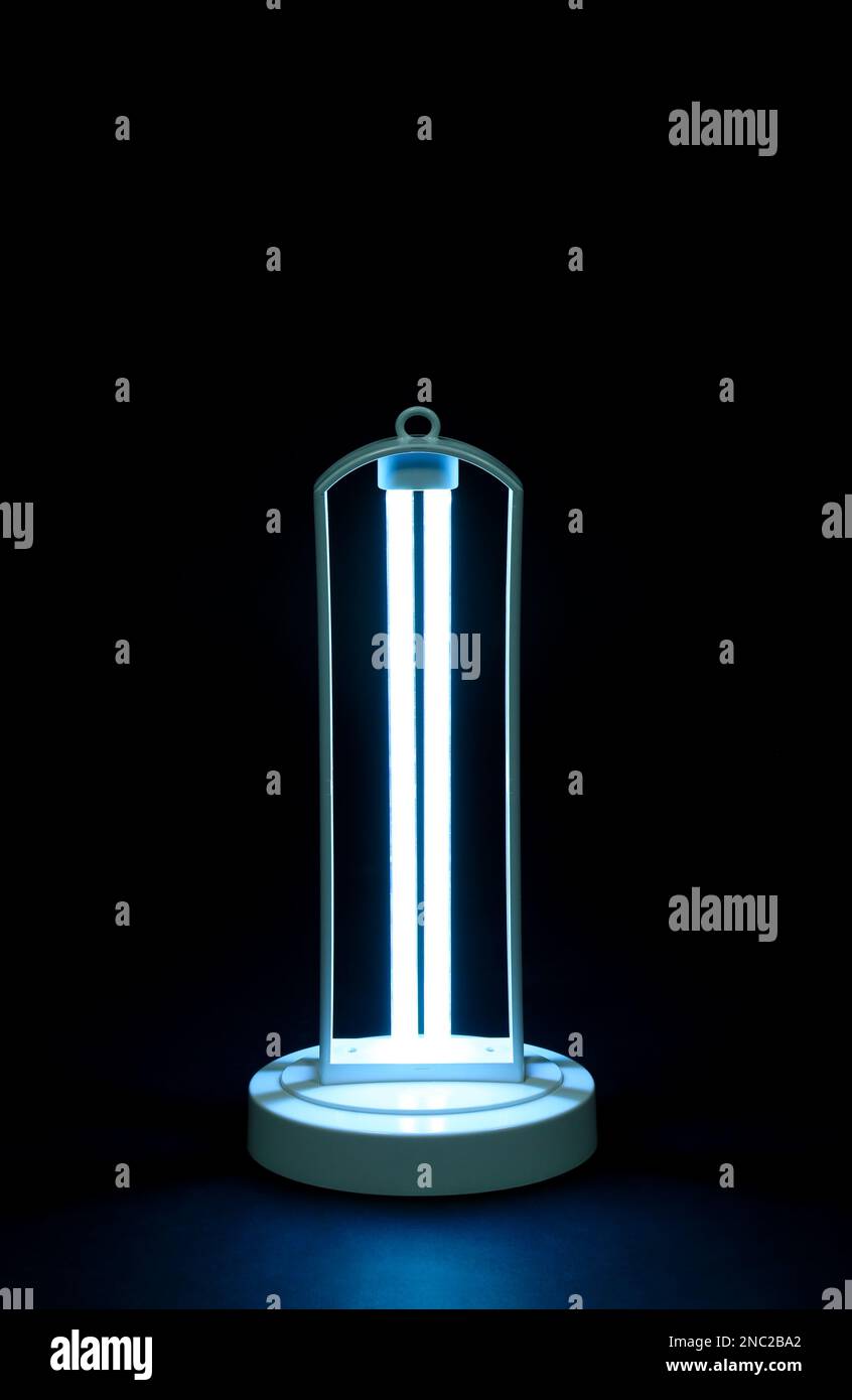 Modern ultraviolet lamp glowing on black background Stock Photo - Alamy