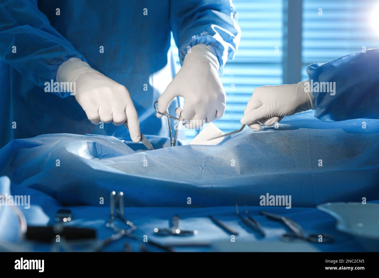 Professional surgeons with instruments performing operation in clinic ...