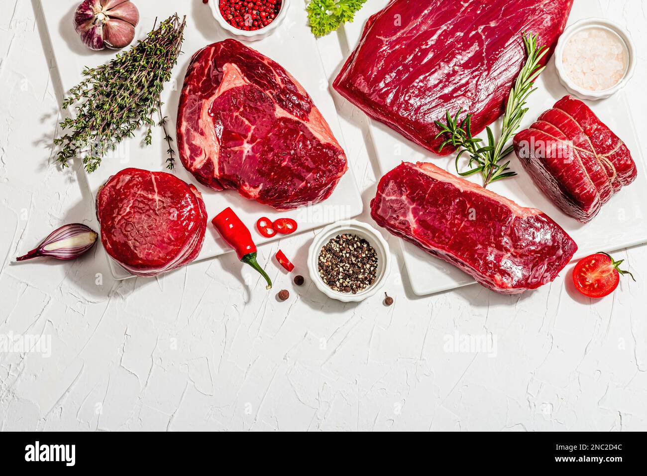 Set of various steaks with spices and herbs. Classic raw meat cuts includes ribeye, eye round ...