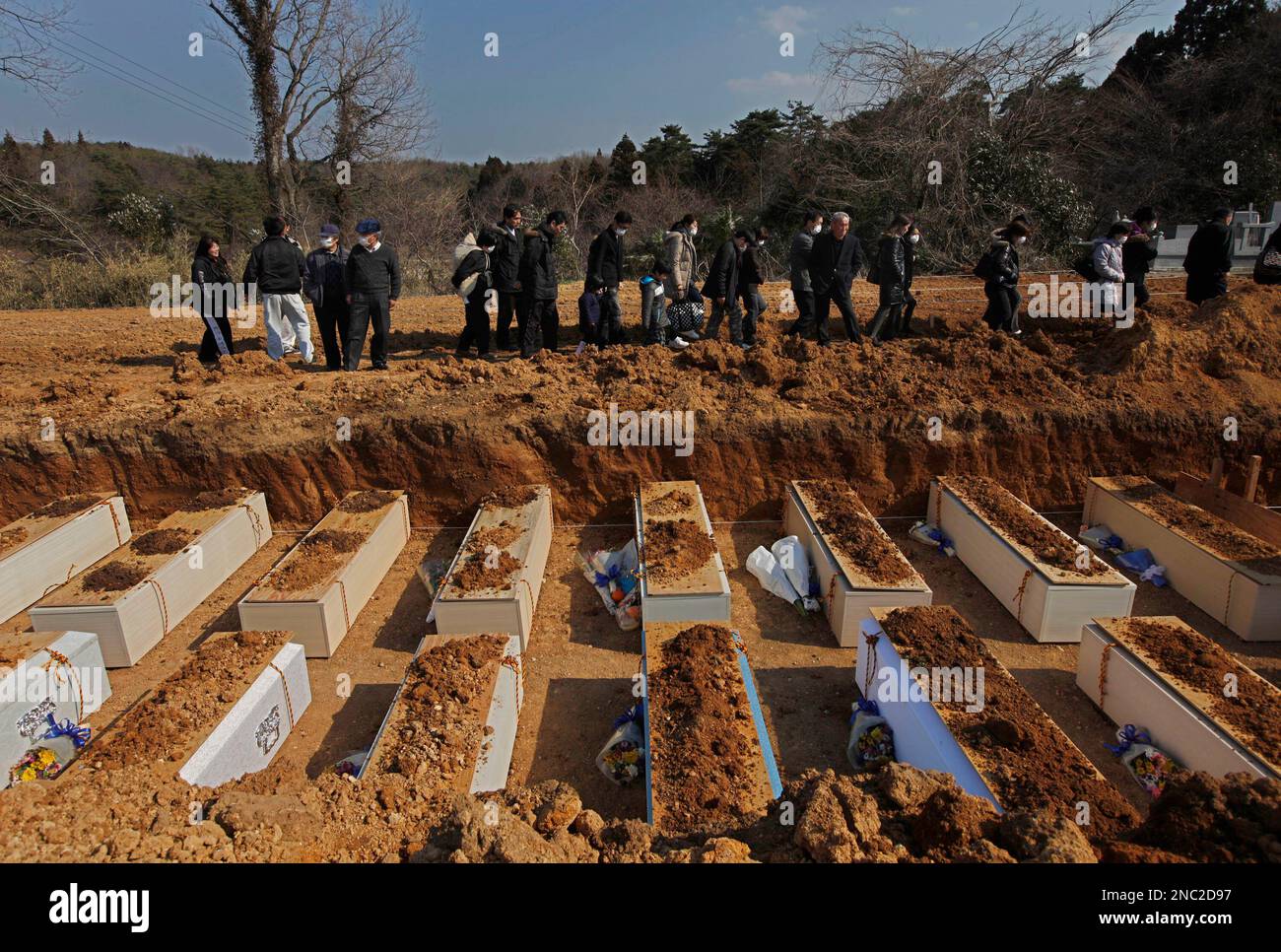 Relatives walk past coffins containing victims of the March 11 ...