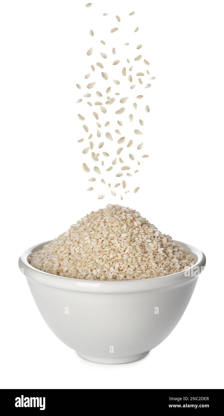 Sesame seeds falling into bowl on white background Stock Photo - Alamy