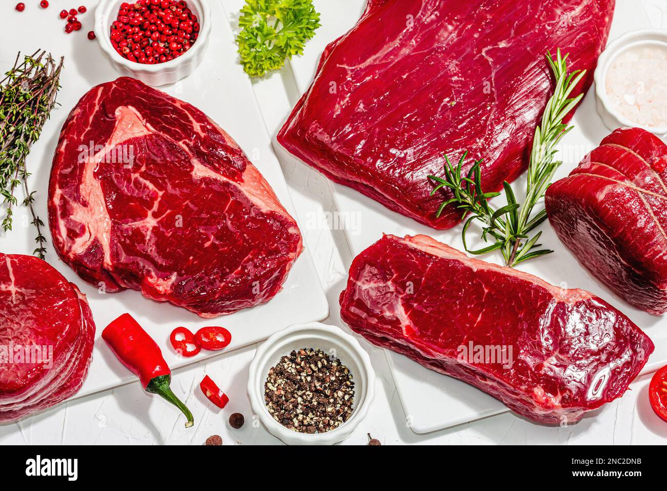 Set of various steaks with spices and herbs. Classic raw meat cuts includes ribeye, eye round ...