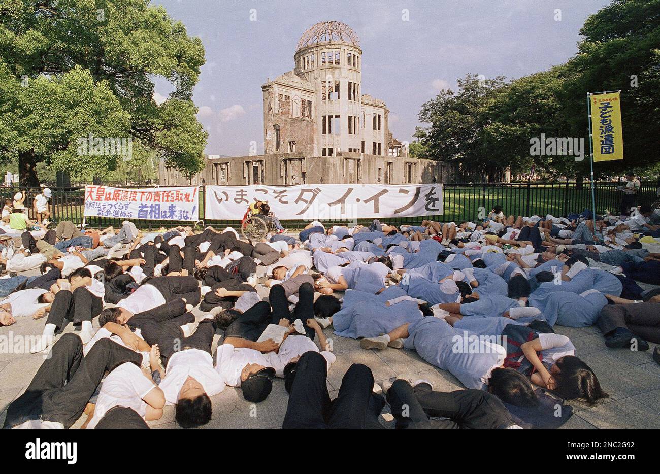High school students lie on the ground in front of the Atomic Bomb Dome ...