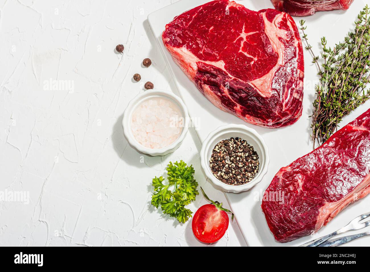 Set of various steaks with spices and herbs. Classic raw meat cuts includes ribeye, eye round ...