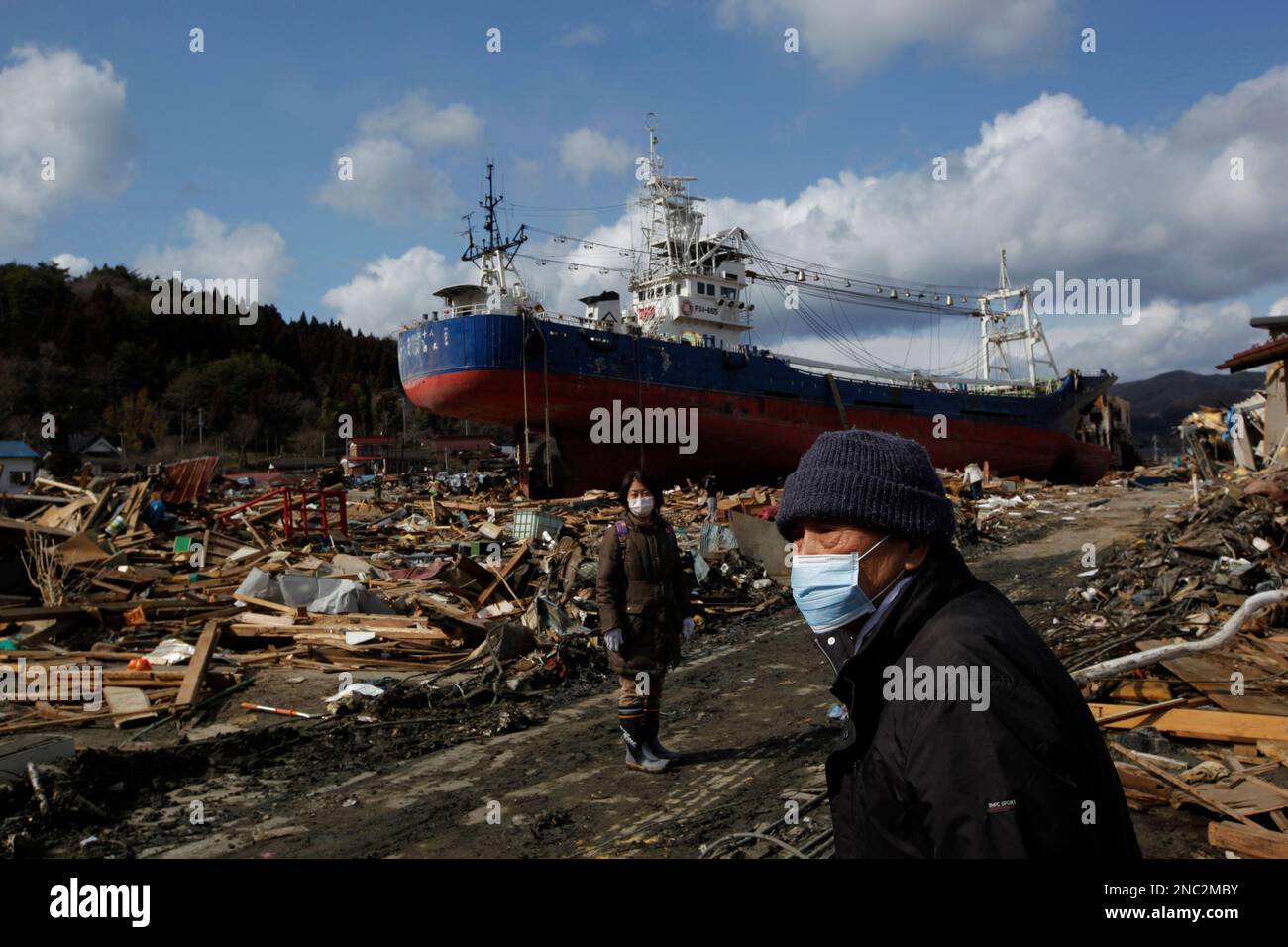Survivos walk in the devastated city of Kesennuma in Miyagi Prefecture ...