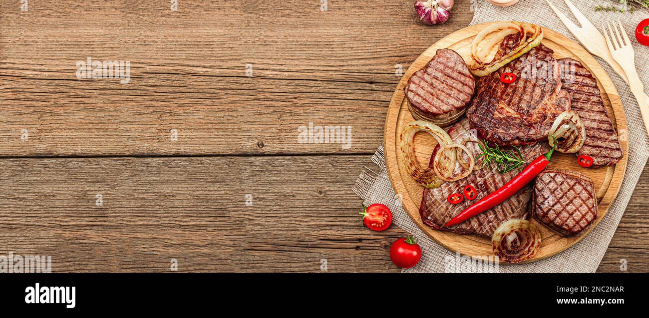 Grilled set of various steaks with vegetables, spices and herbs ...