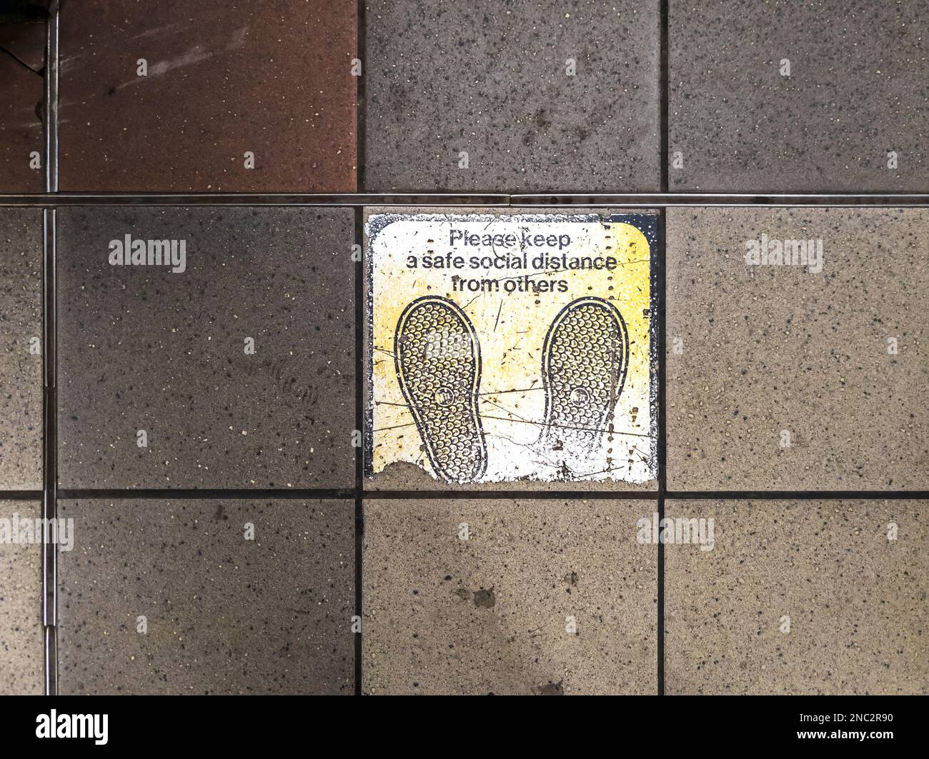 A worn social distancing sticker on the floor of a platform in the ...