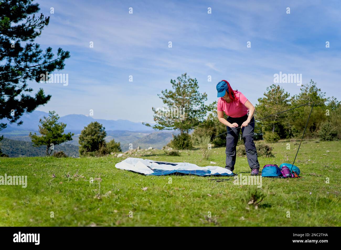 Traveler woman setting up a tent while camping outdoors in nature ...