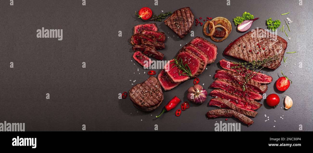 Grilled set of various steaks with vegetables, spices and herbs ...