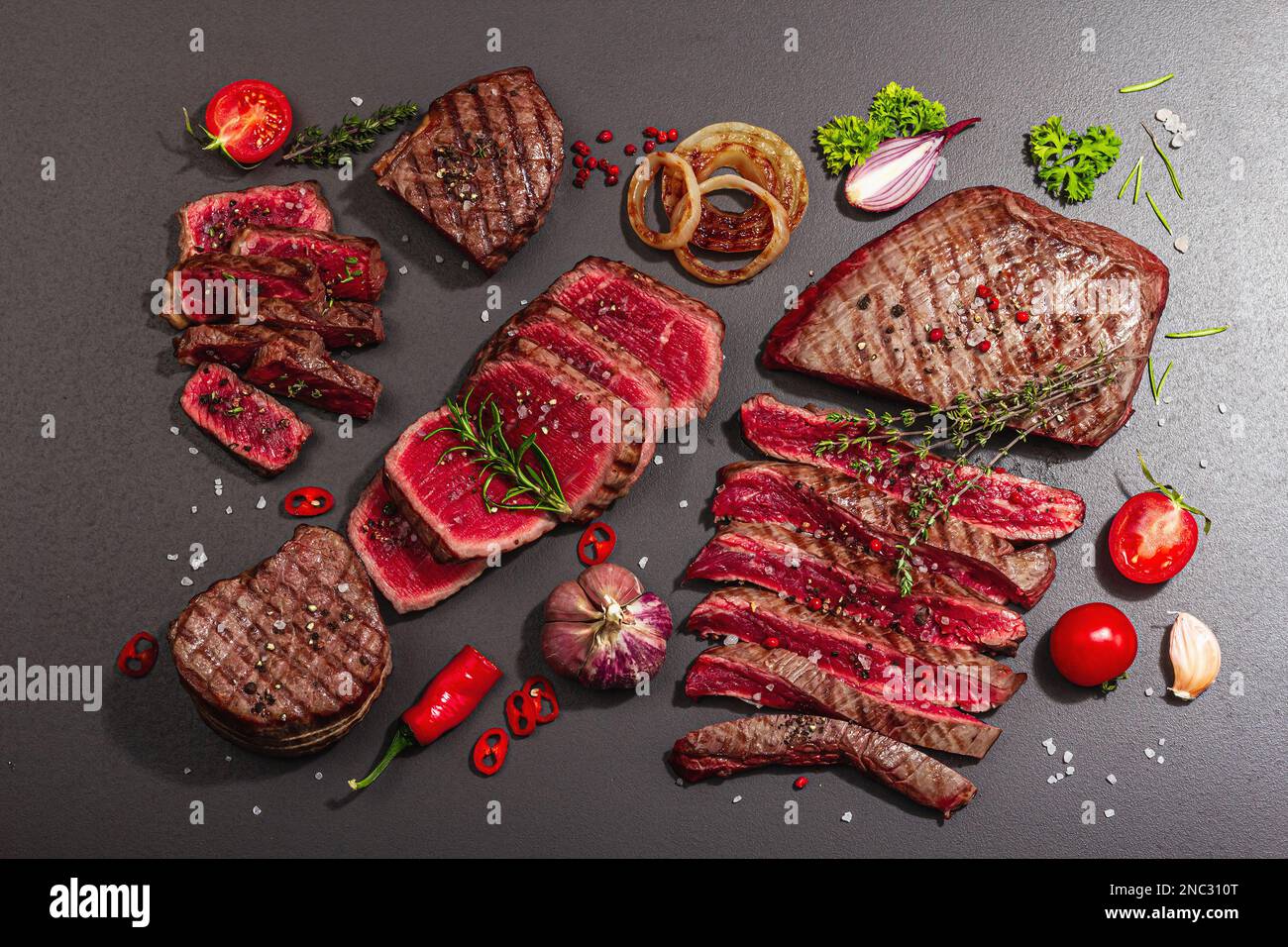 Grilled set of various steaks with vegetables, spices and herbs ...