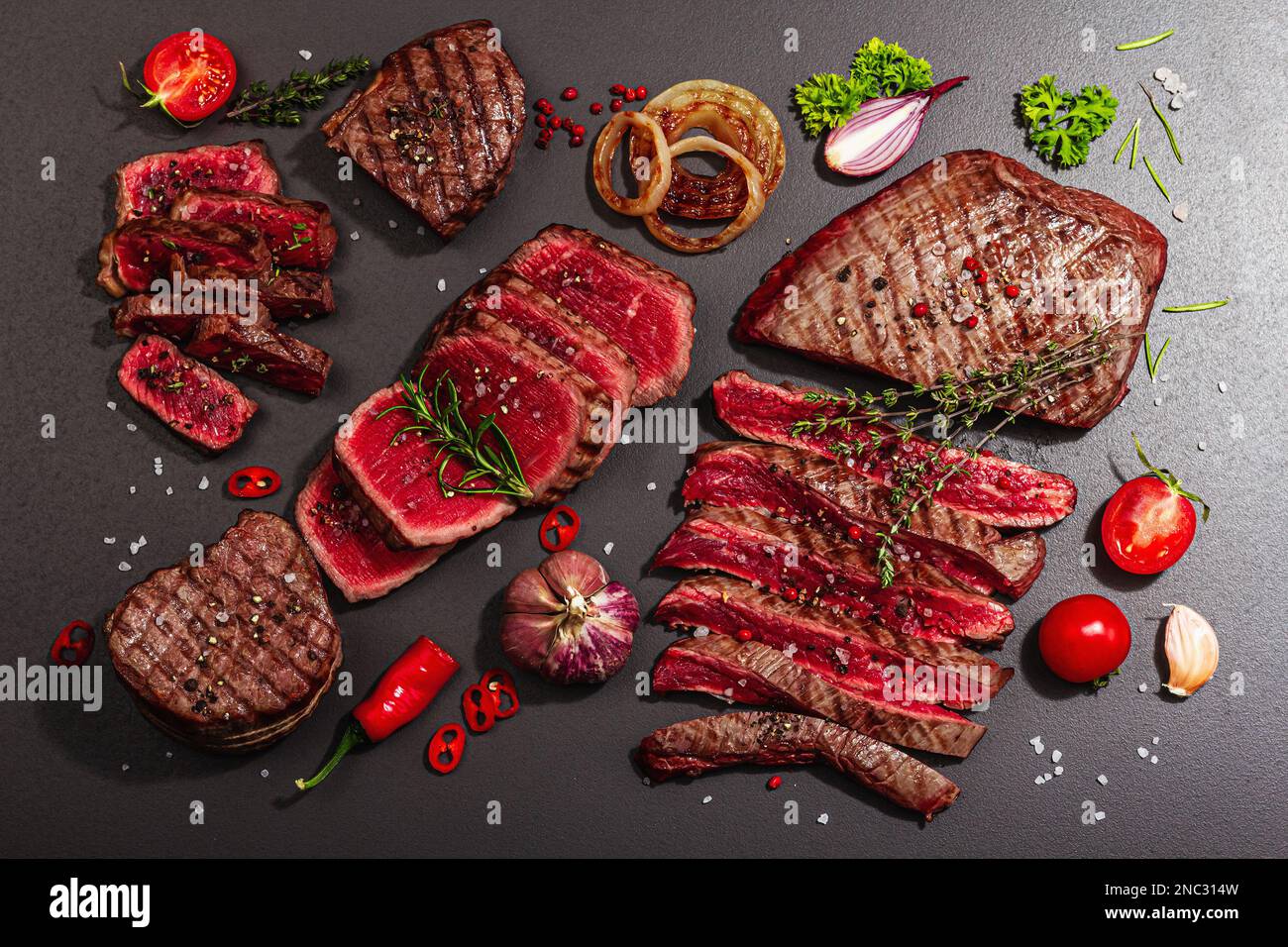 Grilled set of various steaks with vegetables, spices and herbs ...