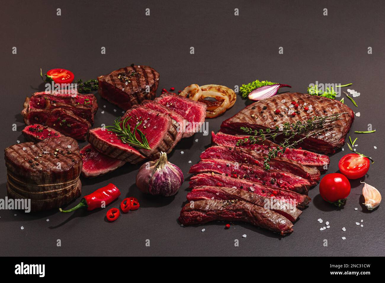 Grilled set of various steaks with vegetables, spices and herbs ...