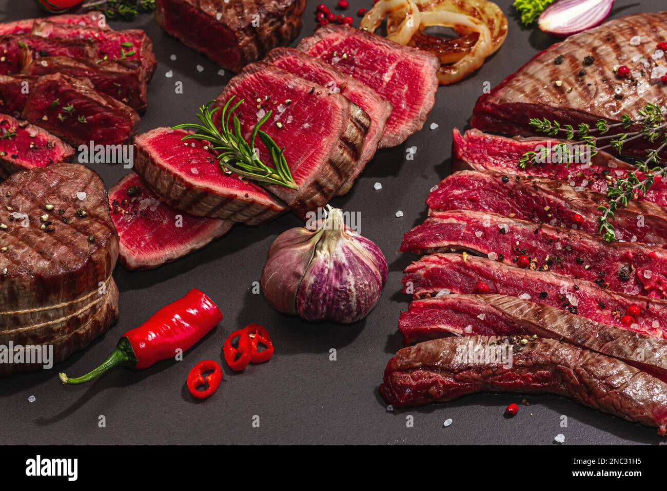 Grilled set of various steaks with vegetables, spices and herbs ...