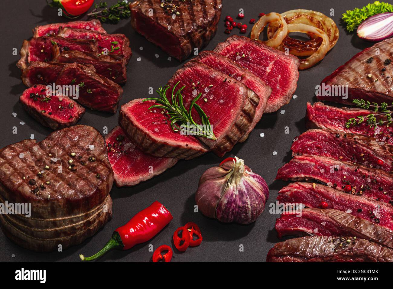 Grilled set of various steaks with vegetables, spices and herbs ...