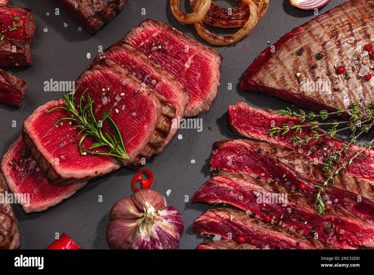 Grilled set of various steaks with vegetables, spices and herbs ...