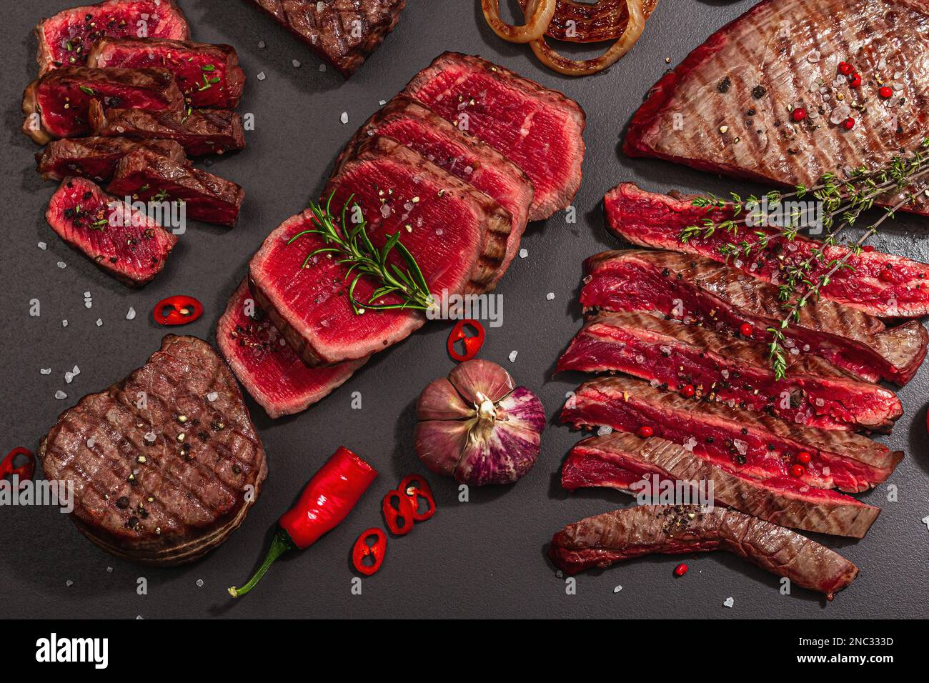 Grilled set of various steaks with vegetables, spices and herbs ...