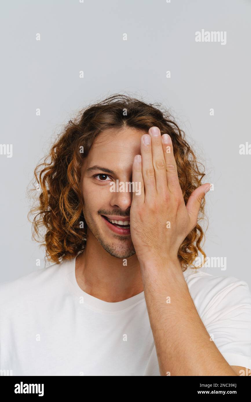 Ginger european man with curly hair smiling and covering his eye ...