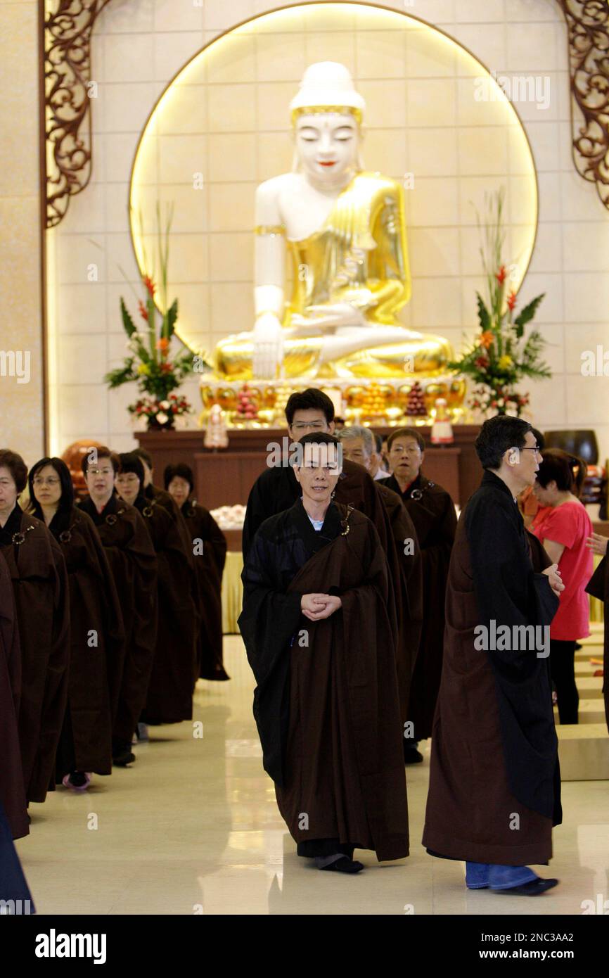 Buddhist devotees walk along the aisle during a prayer for Japanese ...