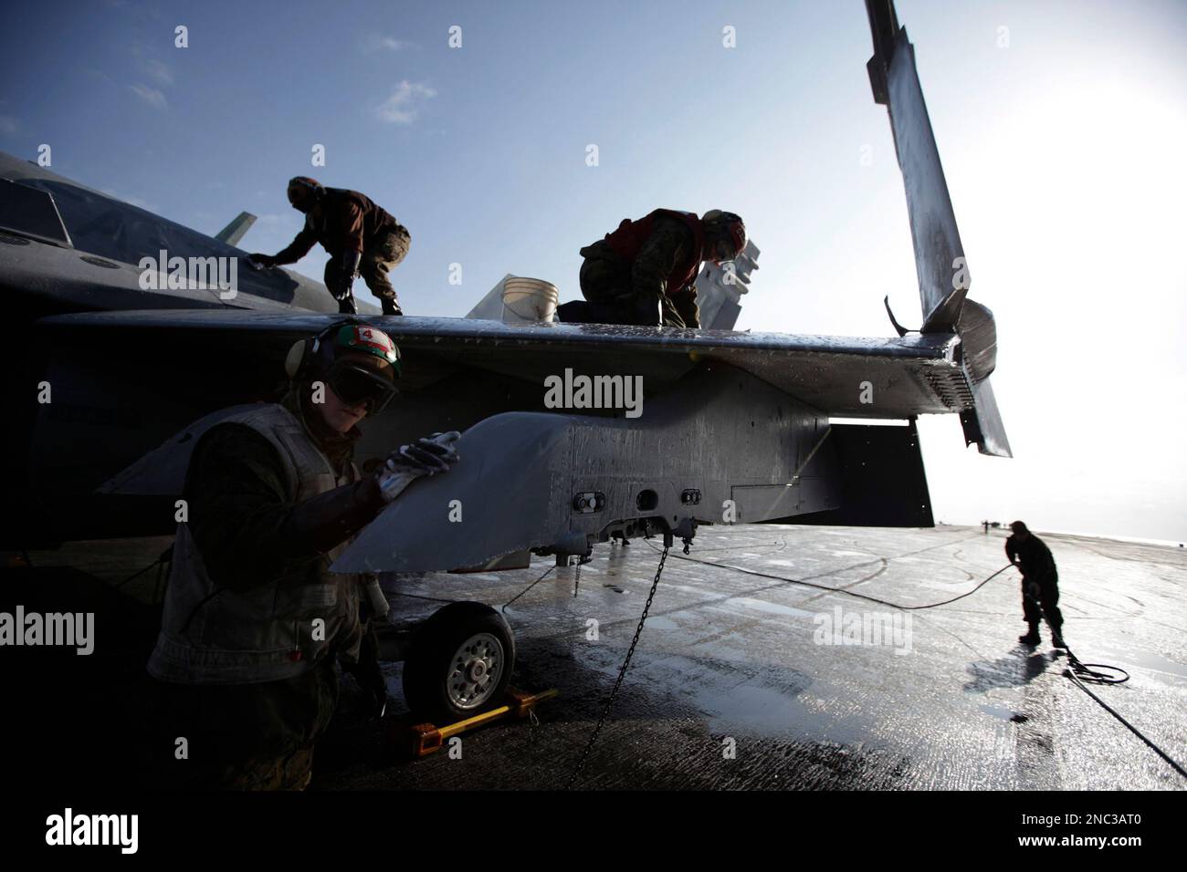 U.S. Navy crew members remove radioactive contamination from a fighter ...