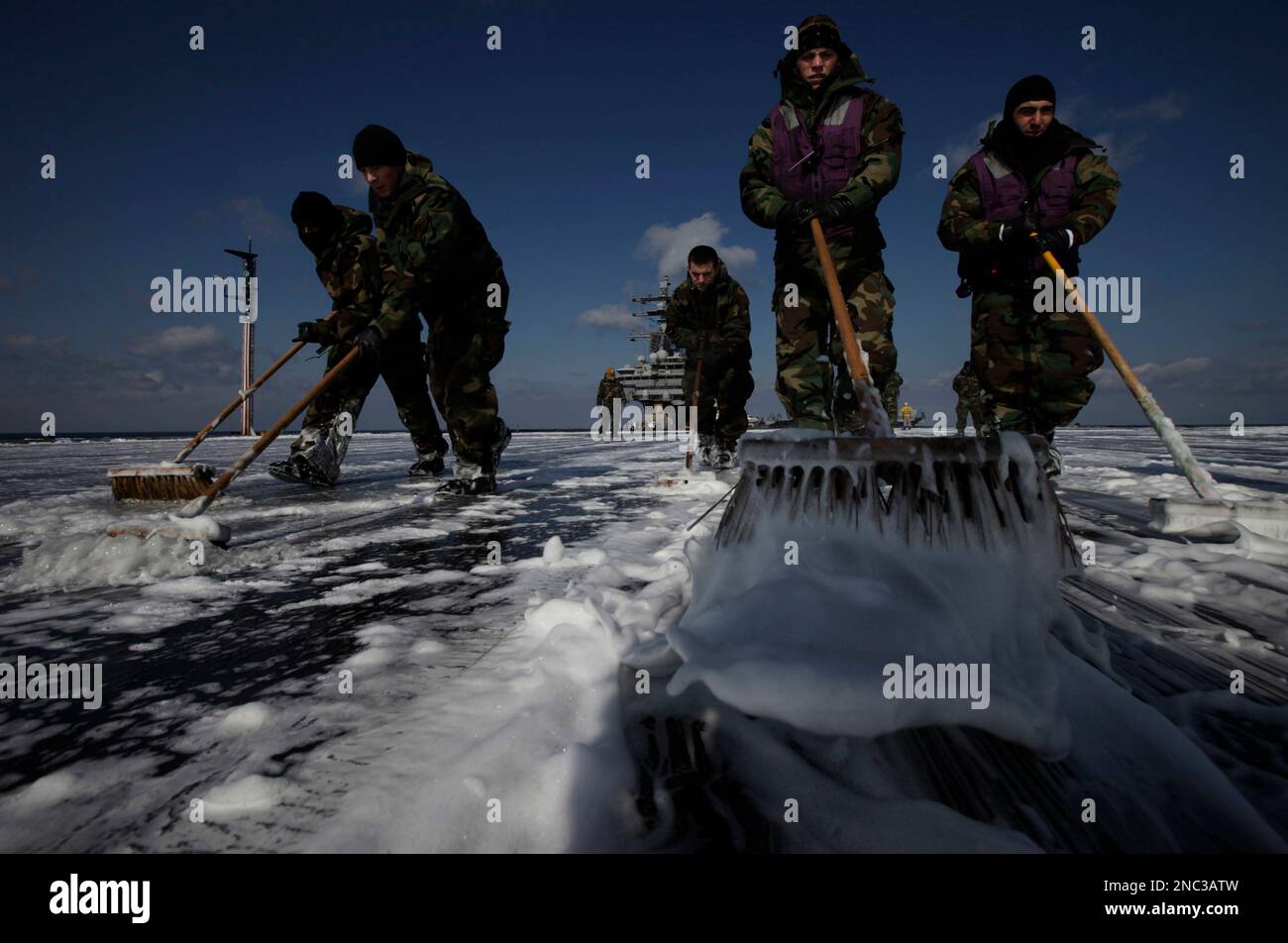 U.S. Navy crew members mop up the flight deck to remove radioactive ...