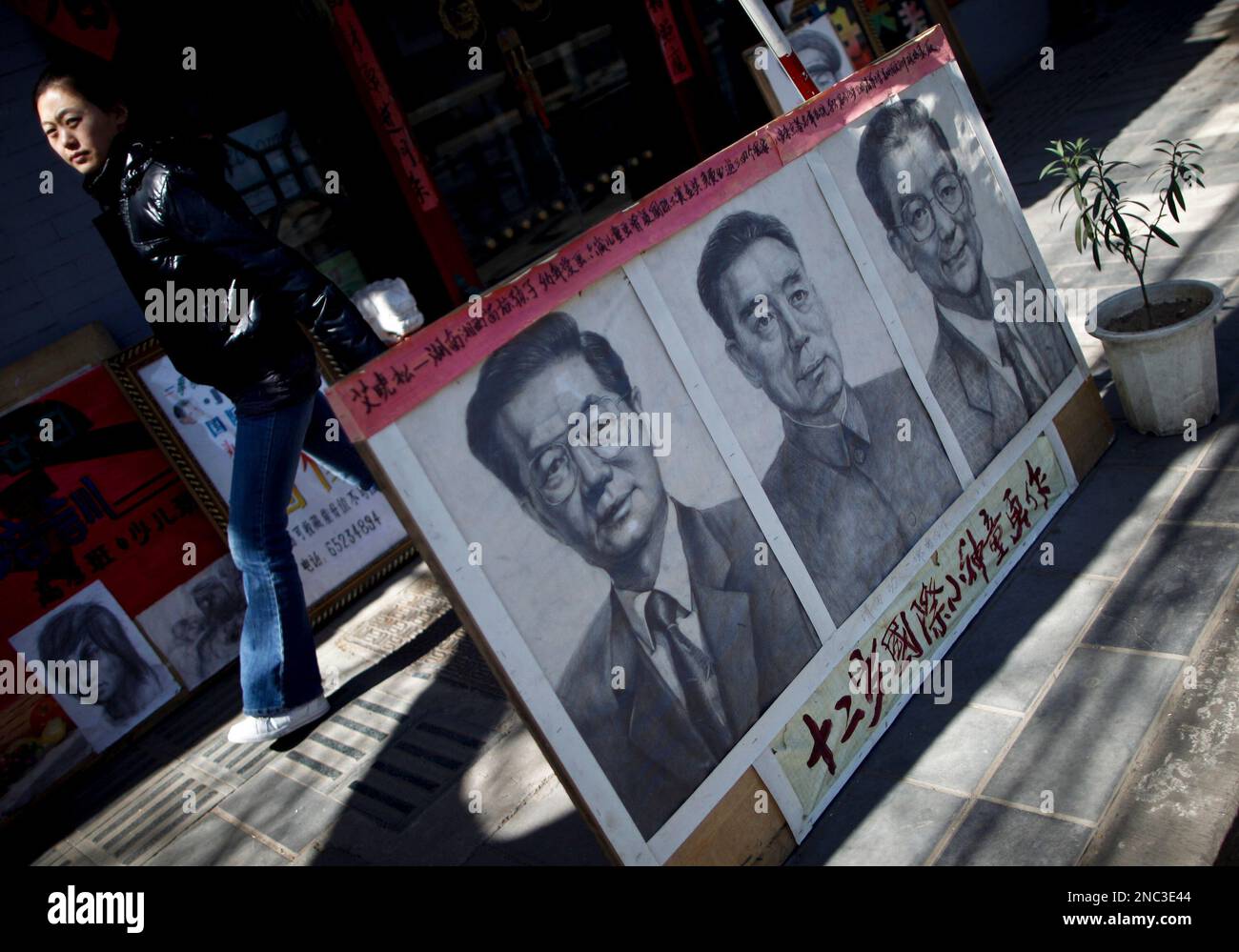 A woman walks past portraits of Chinese President Hu Jintao, from left ...