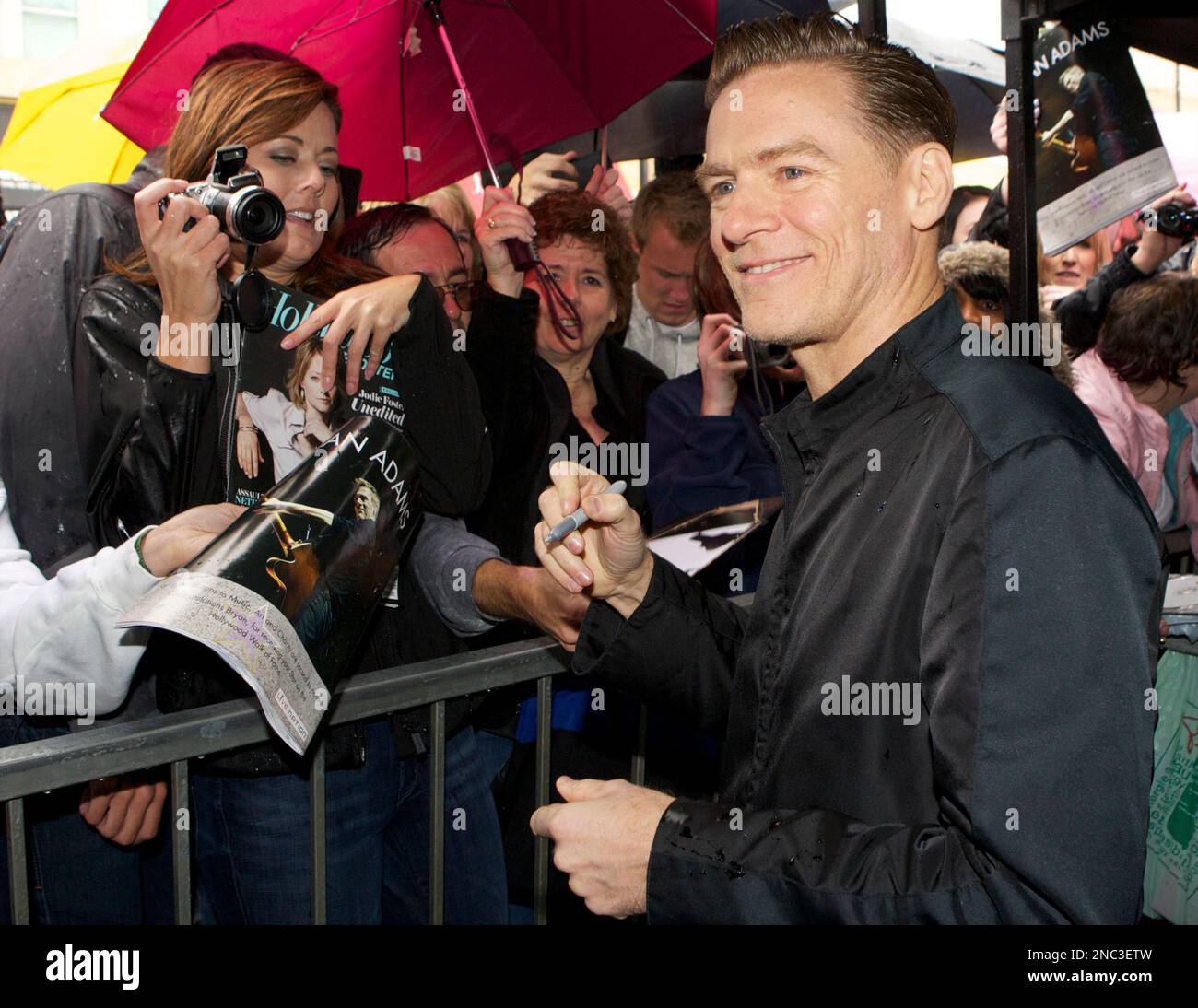 Canadian singer Bryan Adams, right, signs autographs for fans in the ...