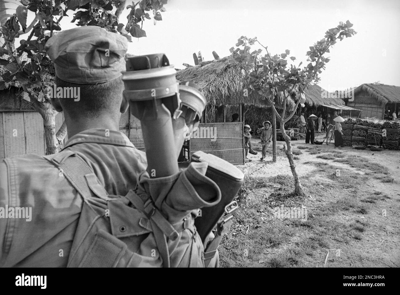 U.S. Marine carrying 4.2 rocket in his pack passes through village as ...