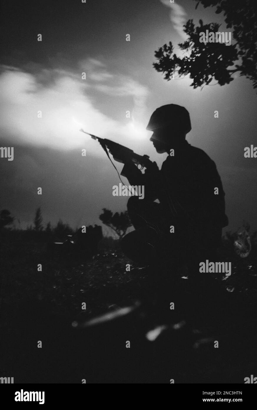 U.S. Marine is silhouetted against a sky lit by flares dropped from U.S ...