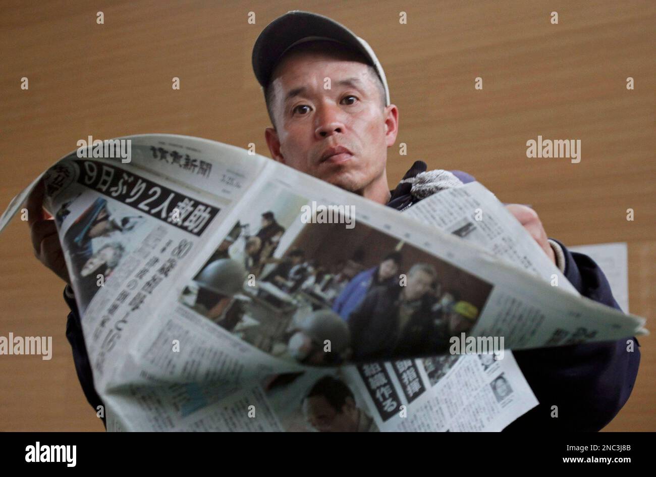 An evacuee holds a newspaper reporting the damage of the March 11 ...