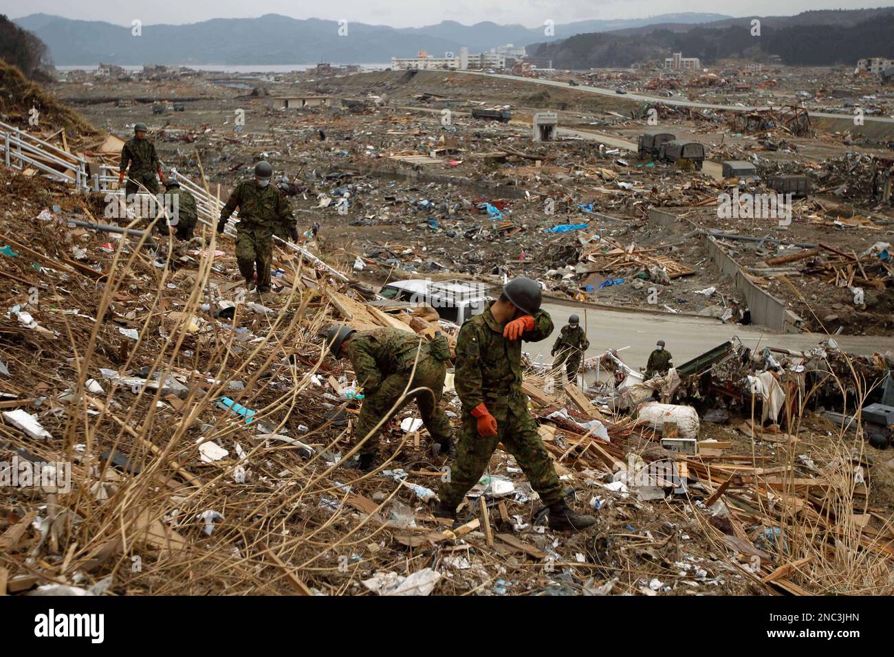 Members of the Japan Ground Self-Defense Force search through debris on ...