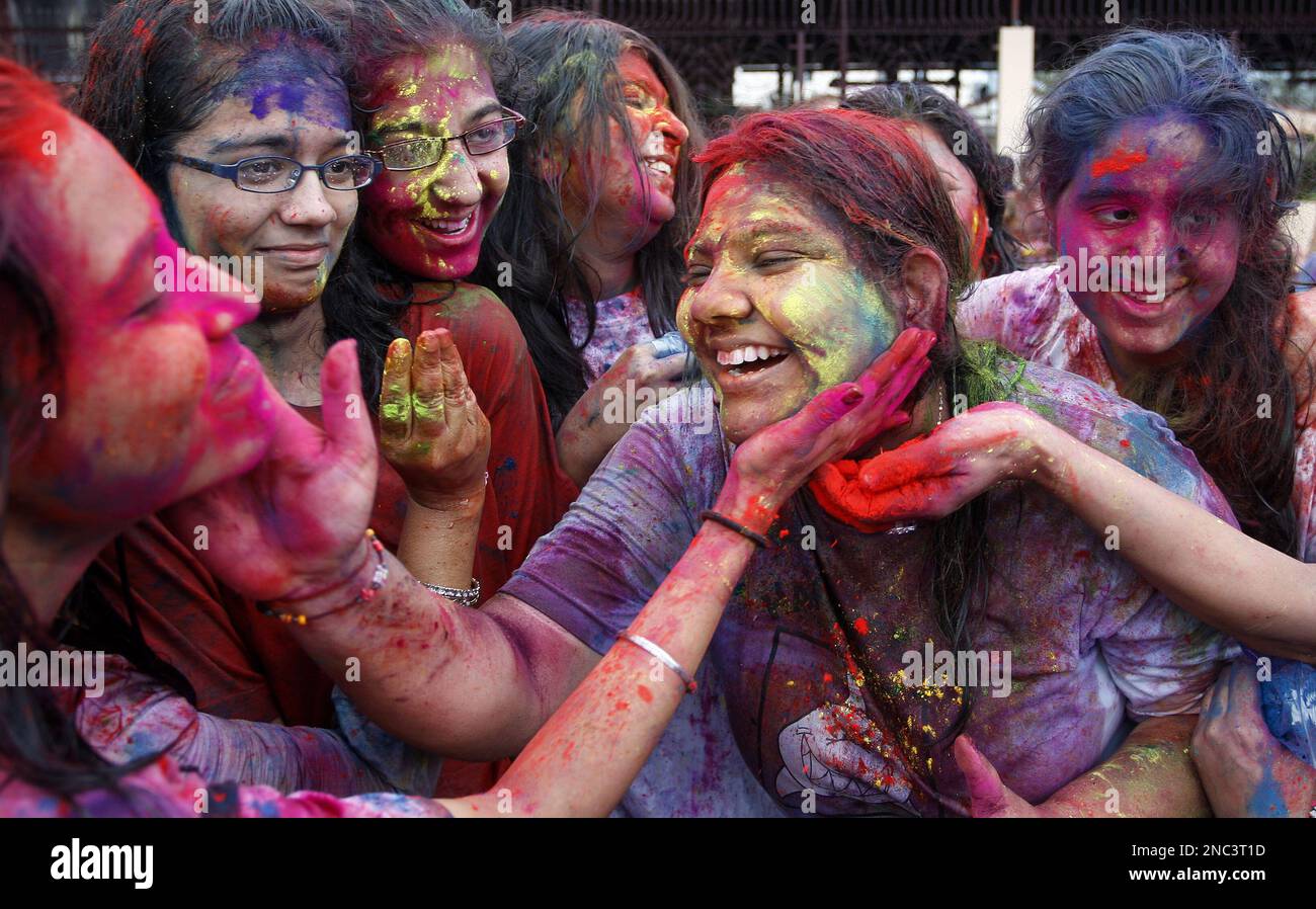 Hindu devotees smear each other's face with colored powder during Holi ...