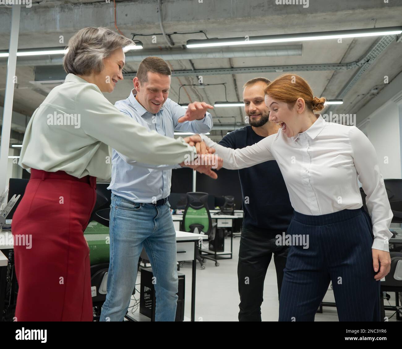 Four colleagues give the low five in the office Stock Photo - Alamy