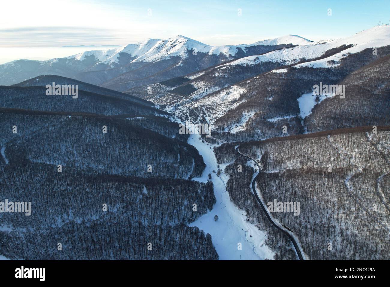 An aerial view of snow covered mountain landscape with dense trees ...
