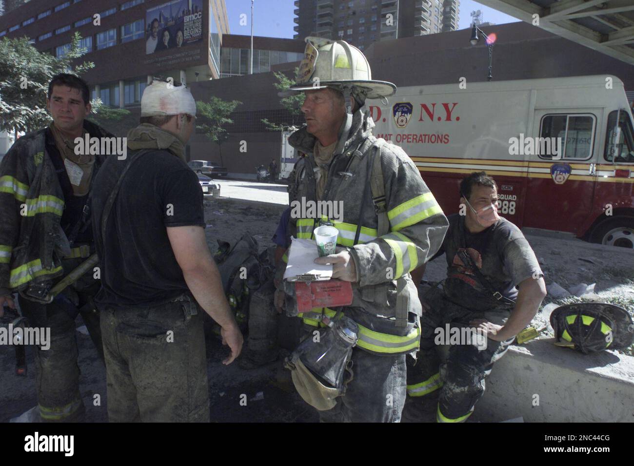 Firemen gather on a debris-covered street after the collapse of the ...