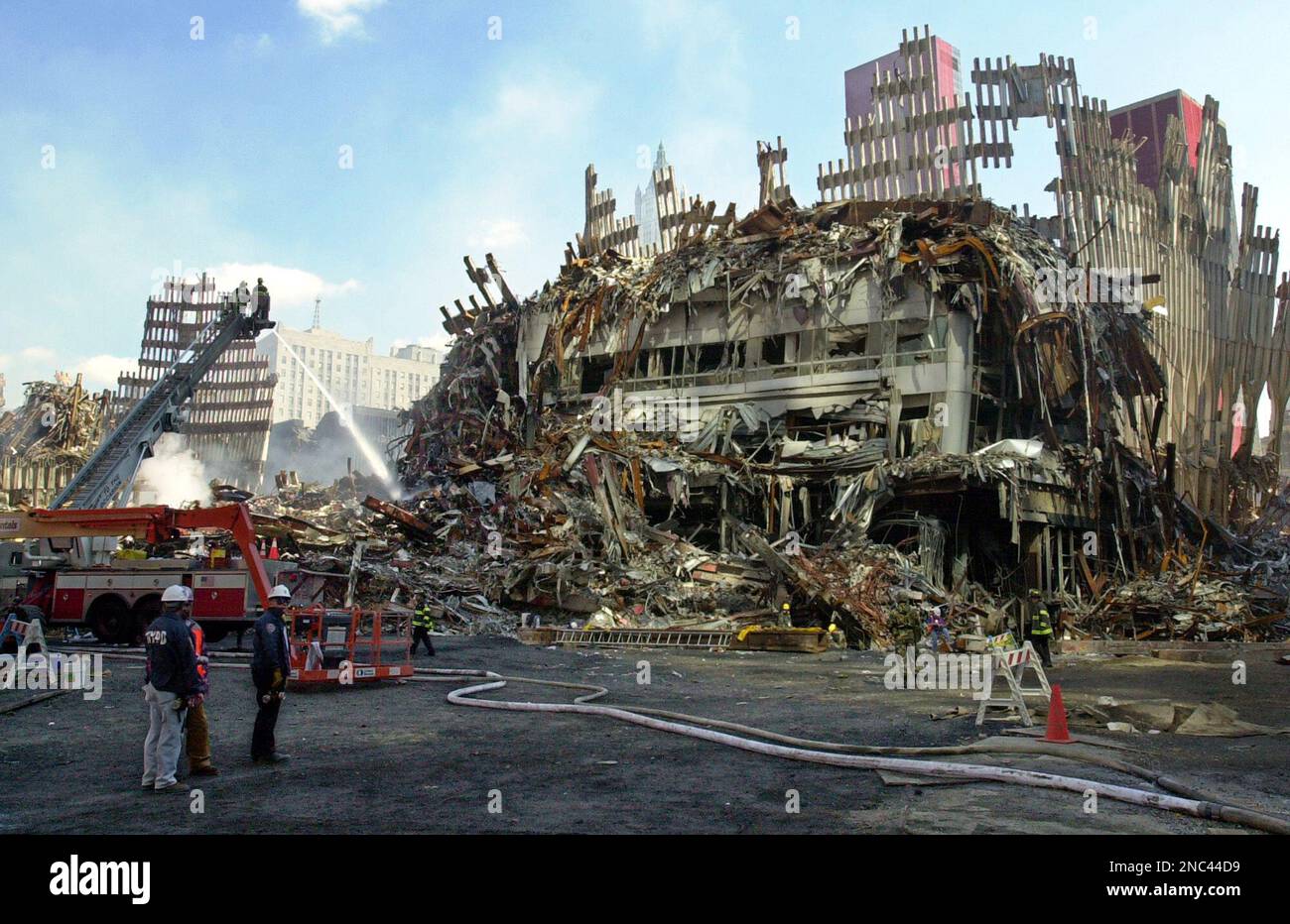 Firefighters pour water on the still smoldering wreckage at Ground Zero ...