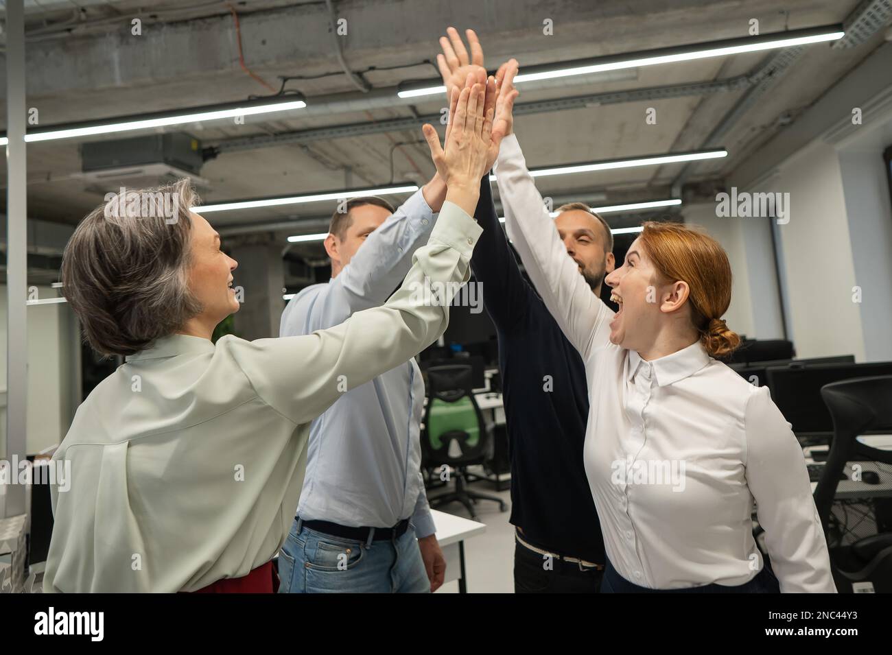 Four co-workers give a high five in the office Stock Photo - Alamy