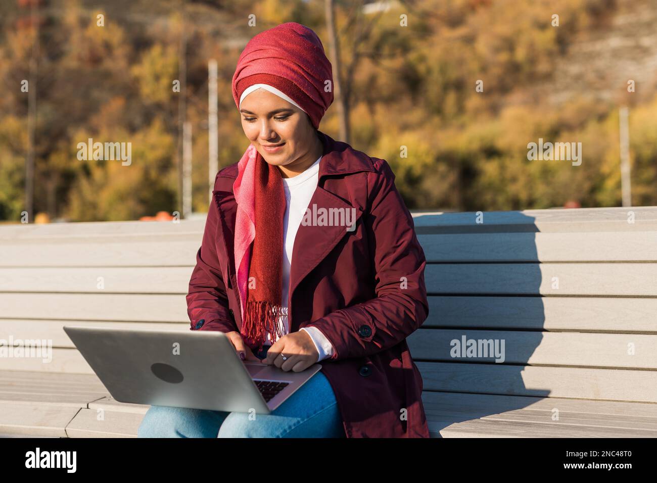 Female muslim arabian student in hijab holding laptop outdoors ...