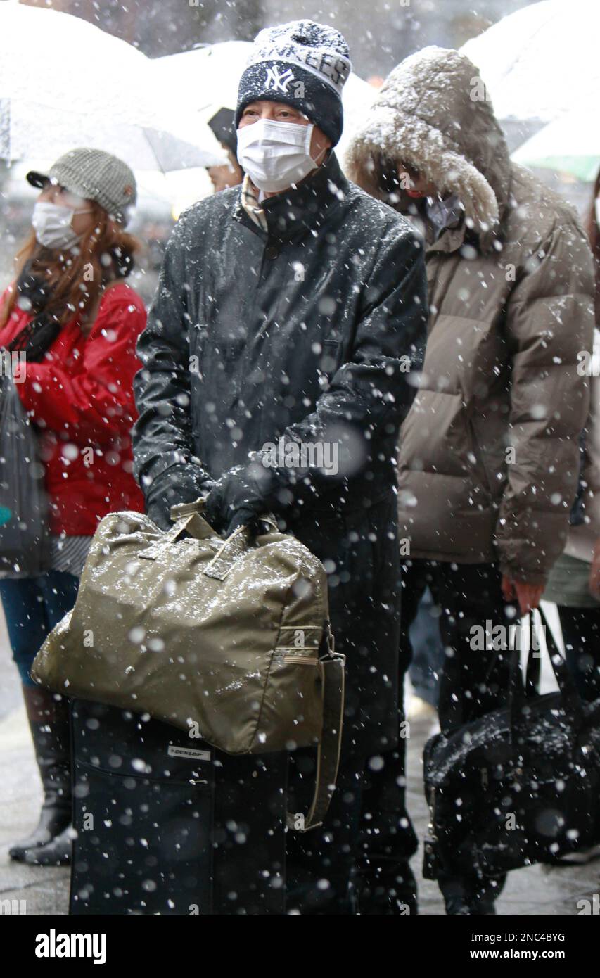 People stand in driving snow as they queue for a bus to leave town in ...