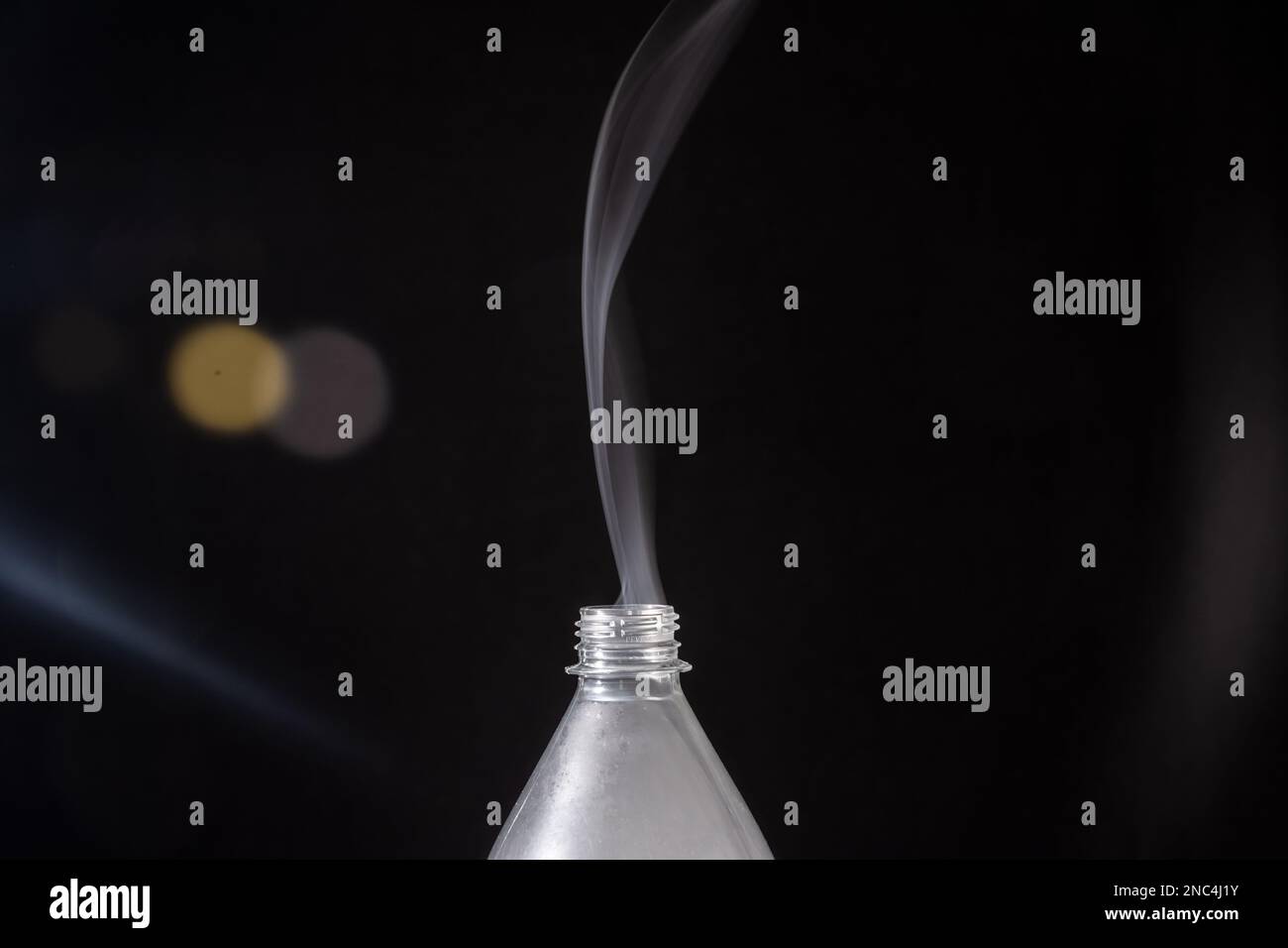 Smoke coming out of a plastic bottle against a black background with ...