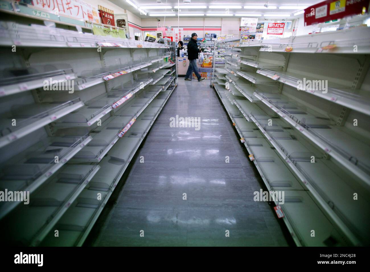 A man shops in a convenience store where shelves on food aisles are ...