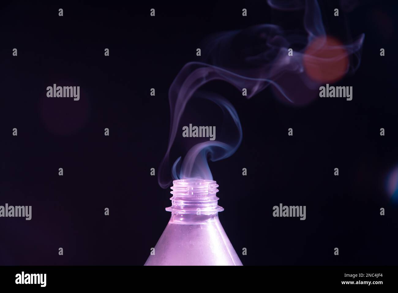 Smoke coming out of a plastic bottle against a black background with ...