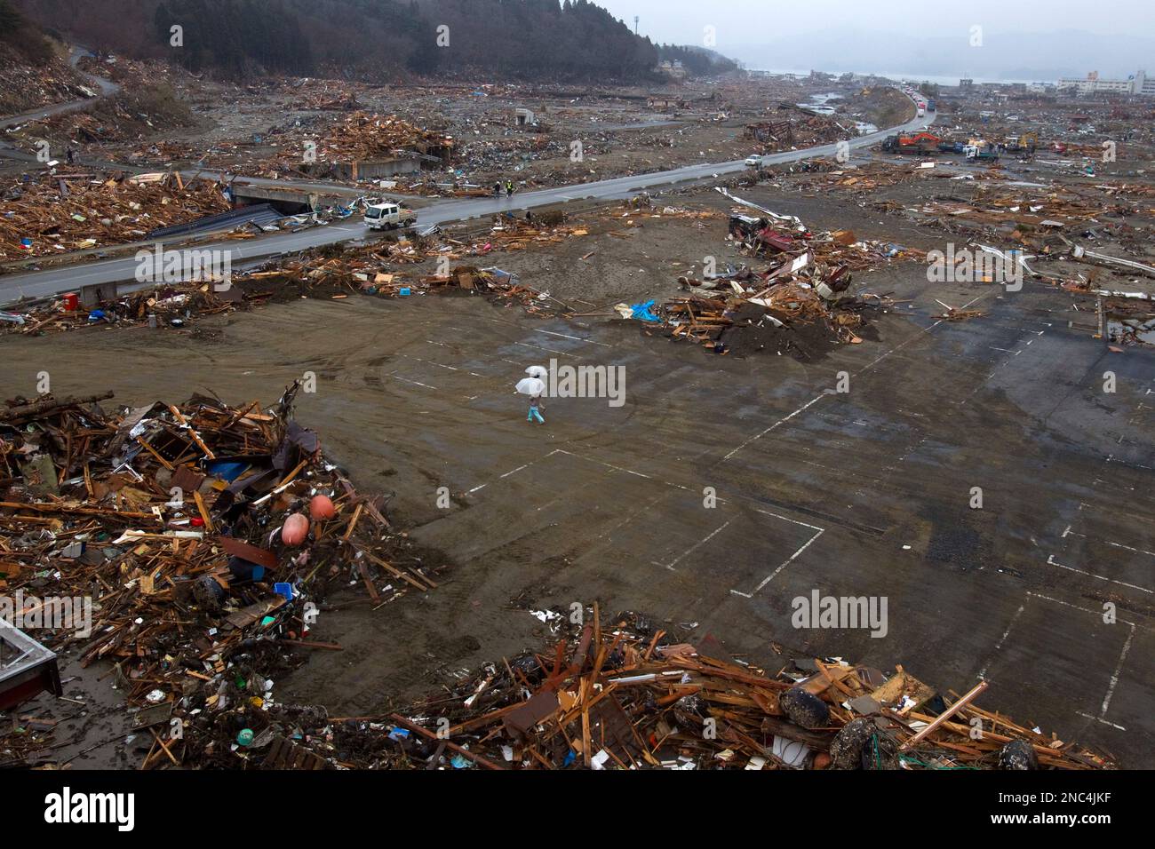 Japanese survivors of Friday's earthquake and tsunami walk under ...