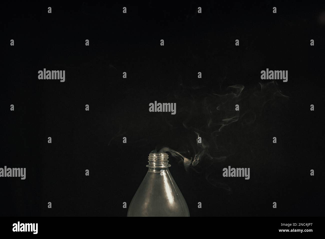 Smoke coming out of a plastic bottle against a black background. Design ...