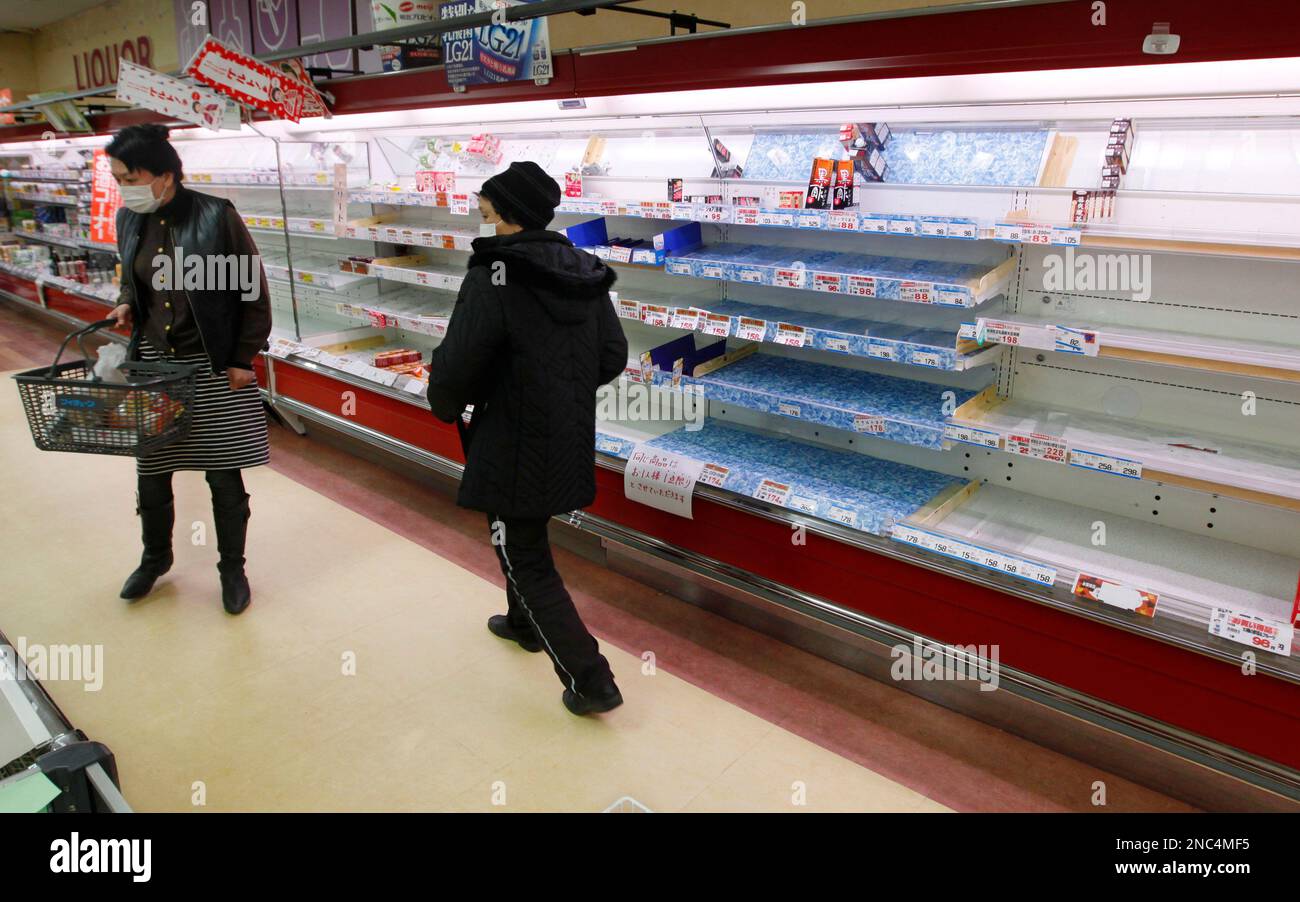 Shoppers look at the empty shelves in a supermarket in Moriyama, Japan ...