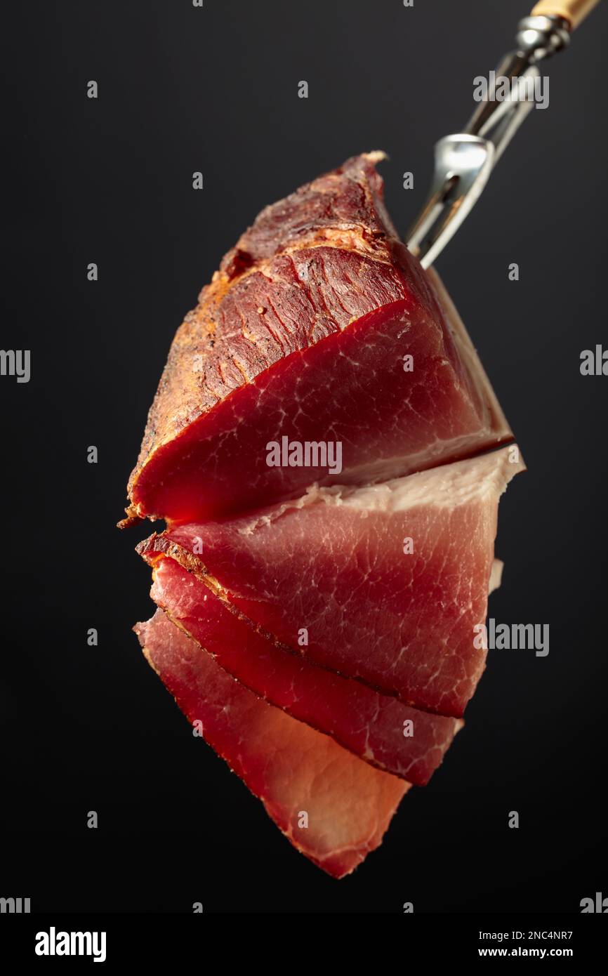 Dry-cured pork fillet on a black background Stock Photo - Alamy