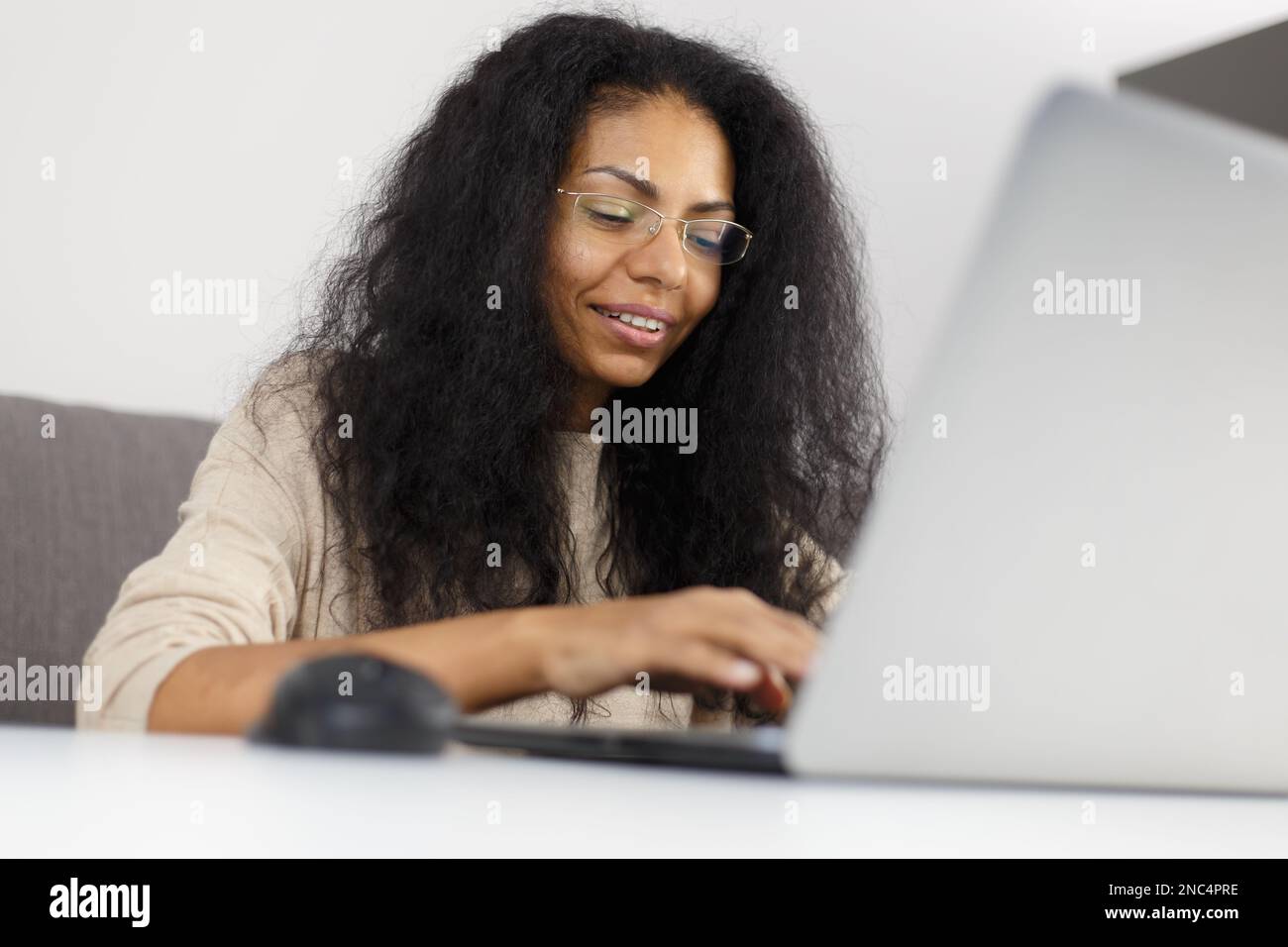 Happy black woman in glasses typing text on computer keyboard. Cheerful ...