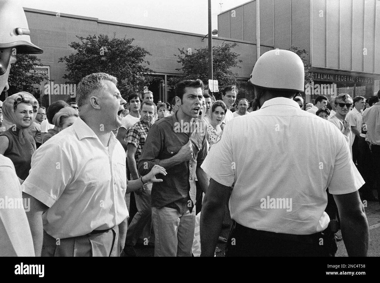 Two men argue violently with a helmeted policeman guarding civil rights ...
