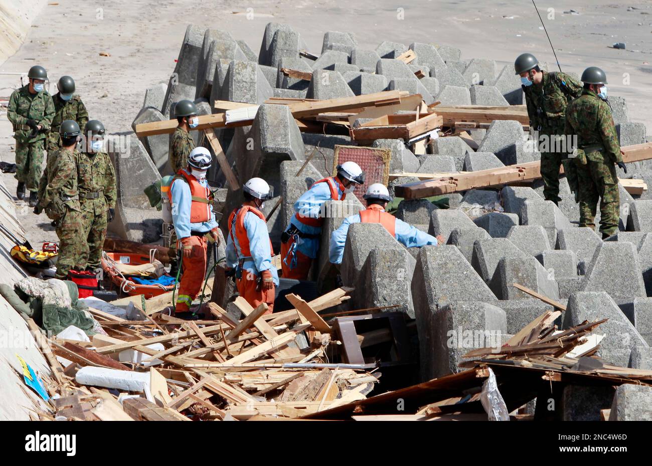 Japanese emergency crews work to free a body as it sits pinned among ...