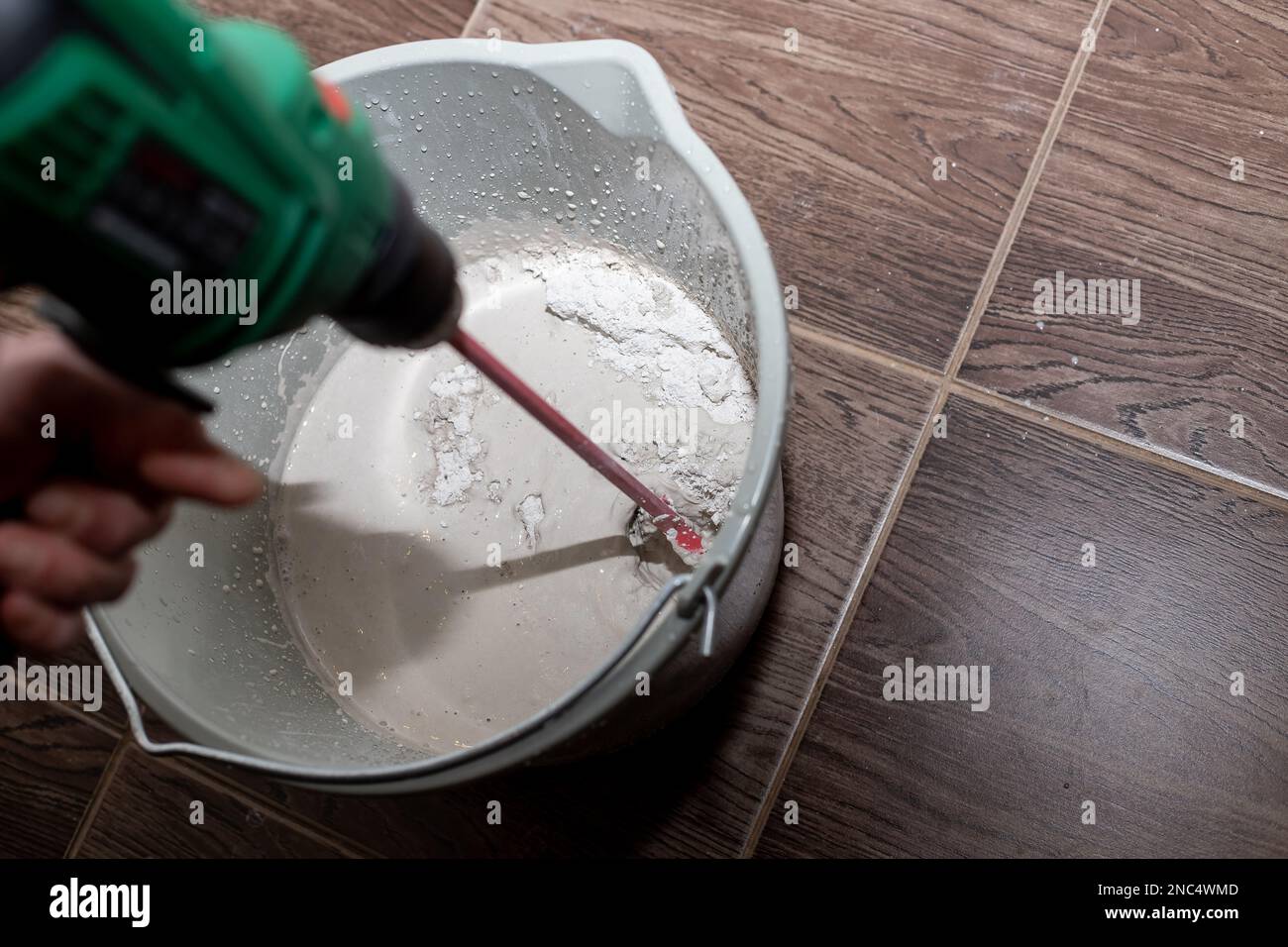 worker mixing plaster in a bucket with electric drill. a plaster ...