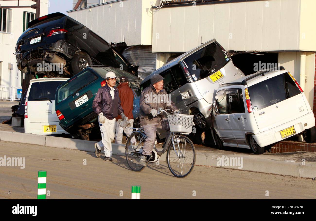 A resident cycles past wrecked cars in the seaside town of Yotsukura ...